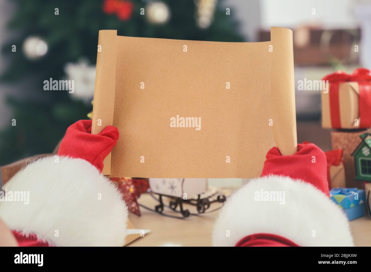 Authentic Santa Claus holding scroll at wooden table Stock Photo - Alamy