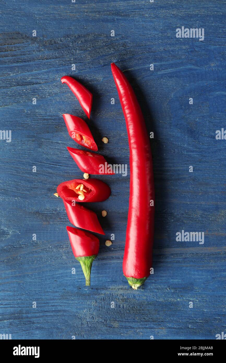 Whole and sliced red chili peppers on wooden background Stock Photo - Alamy