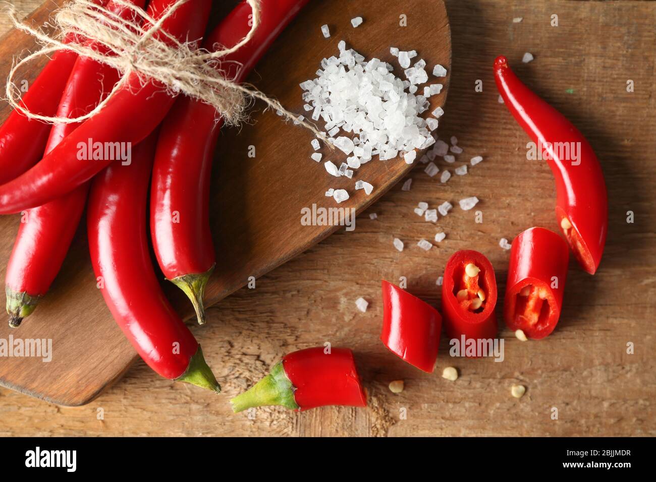 Red chili peppers and sea salt on wooden board Stock Photo - Alamy