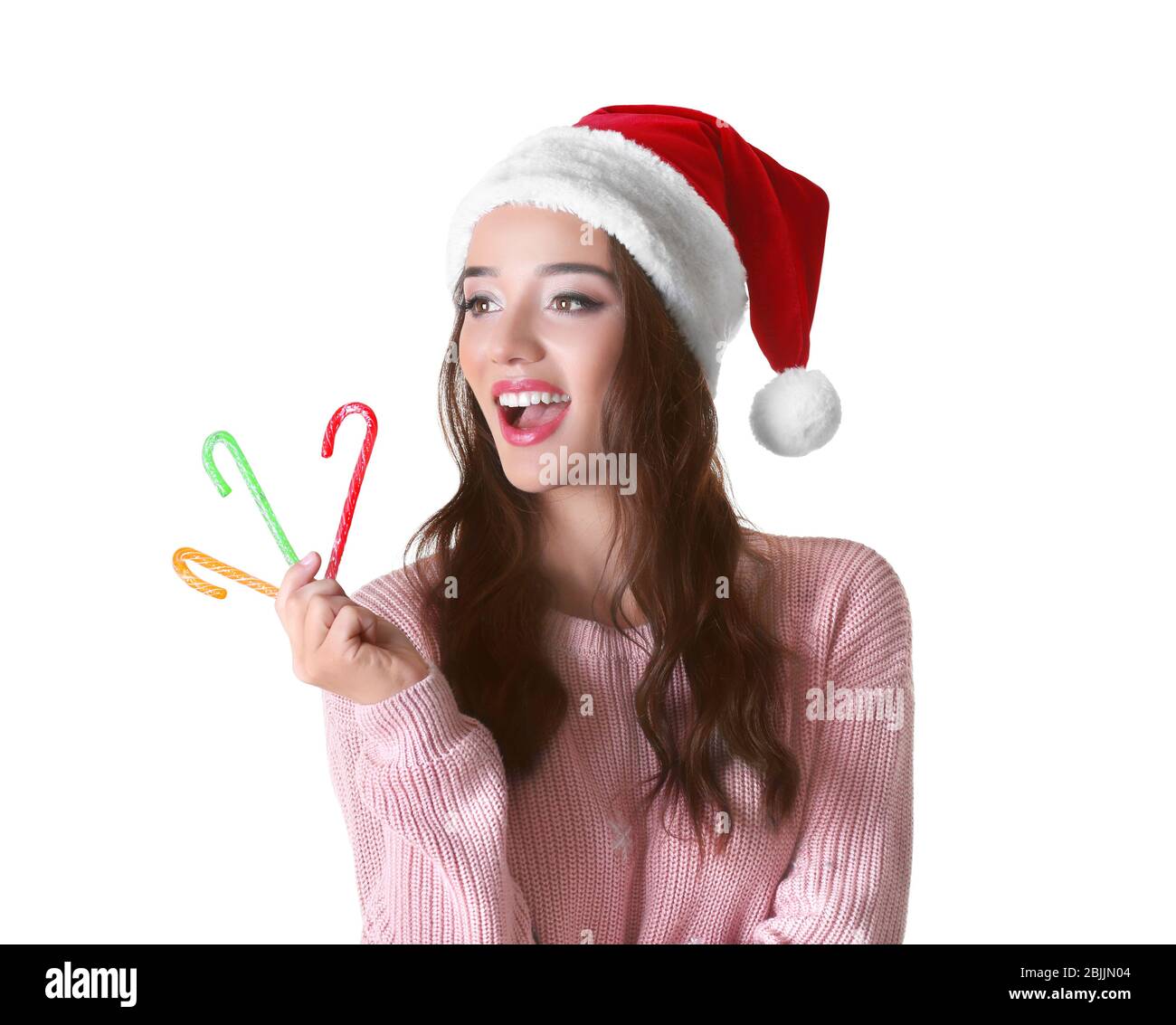 Pretty lady in Christmas hat holding candy canes on white background ...