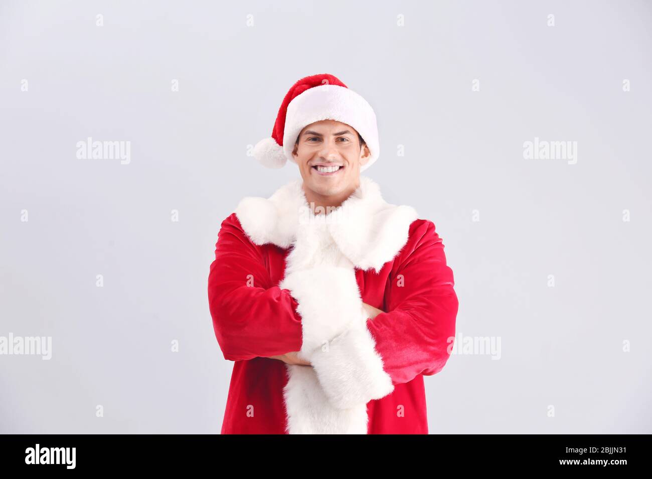 Handsome man in Santa Claus costume on light background Stock Photo - Alamy