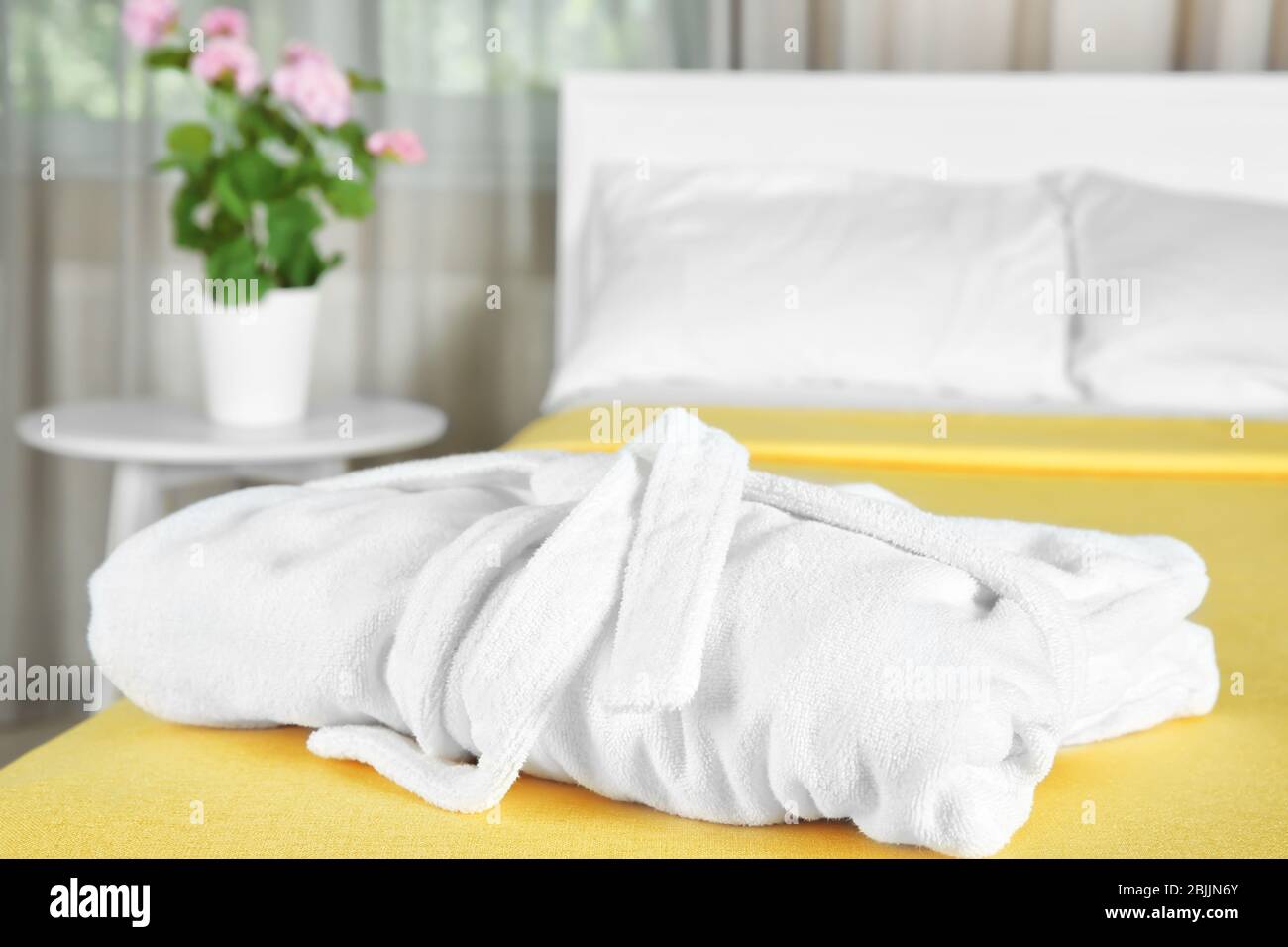 Folded bathrobe on bed in room Stock Photo - Alamy