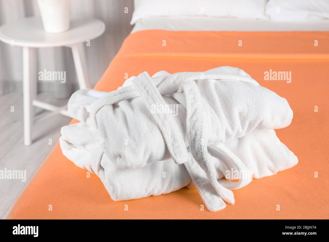 Folded bathrobes on bed in room Stock Photo - Alamy
