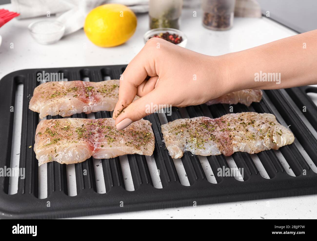 Woman cooking raw fish in kitchen Stock Photo - Alamy