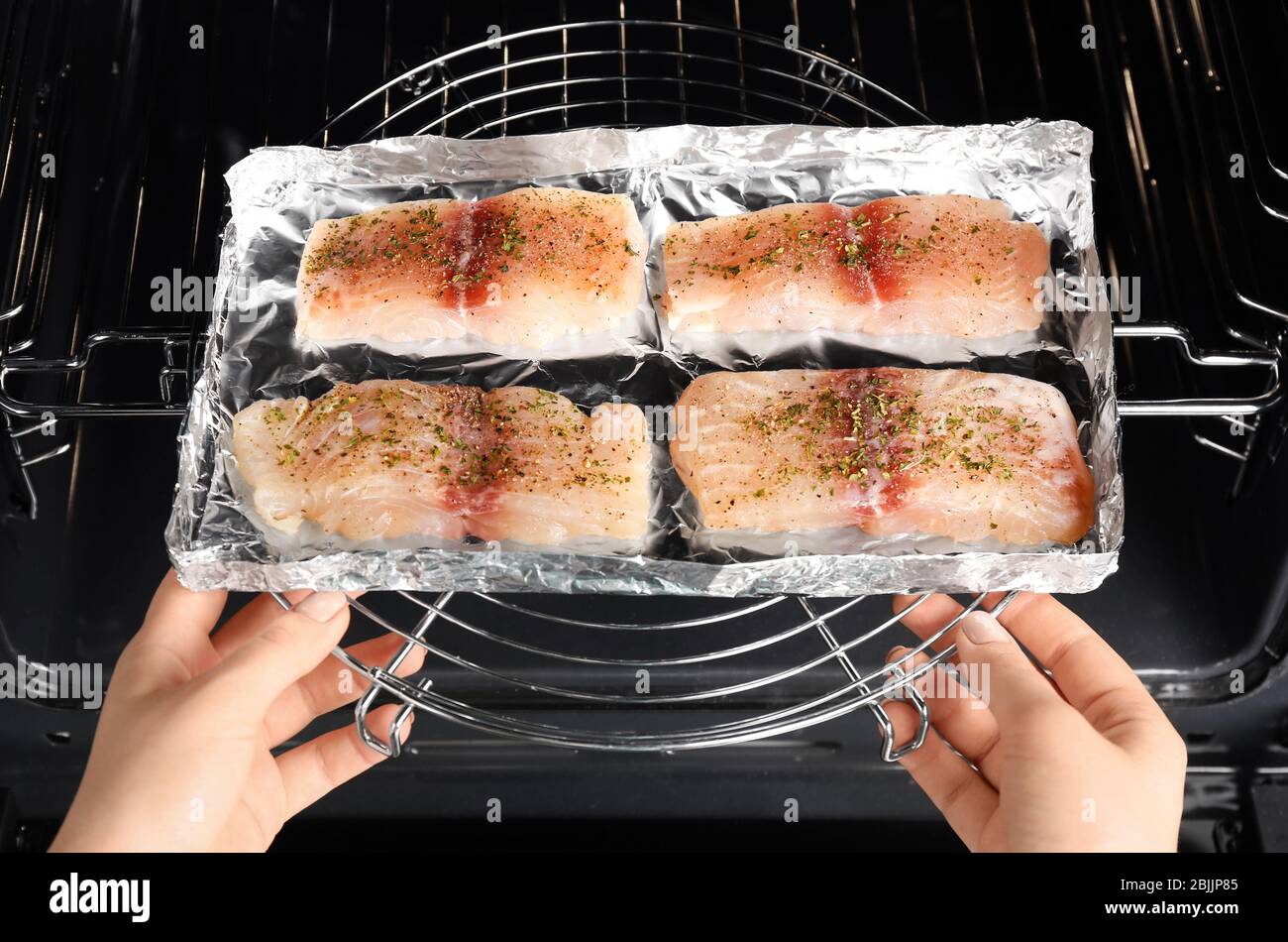 Woman cooking raw fish in kitchen Stock Photo - Alamy