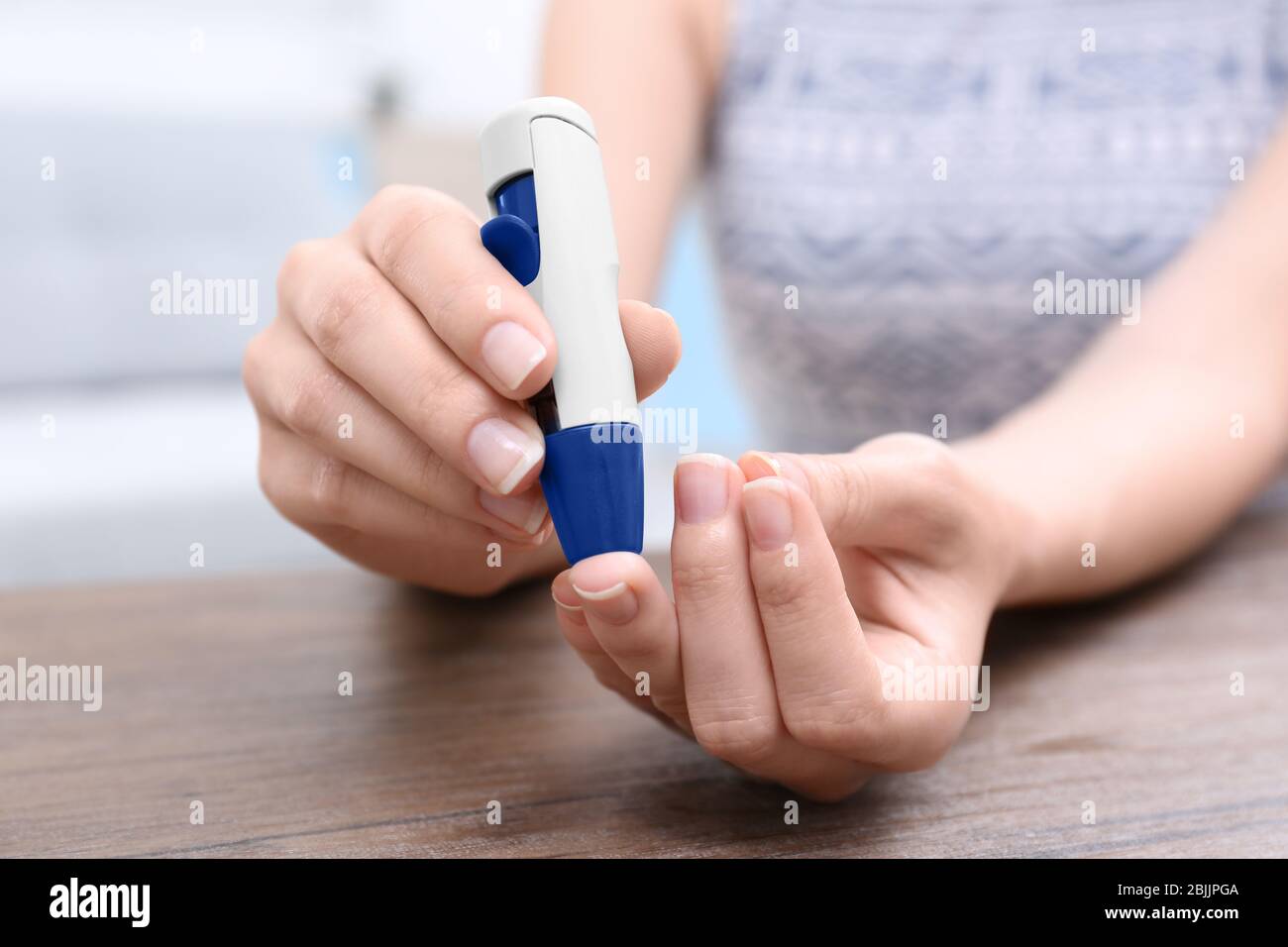 Woman taking blood sample with lancet pen indoors Stock Photo - Alamy