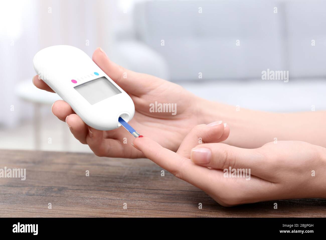 Woman testing glucose level with digital glucometer indoors Stock Photo ...