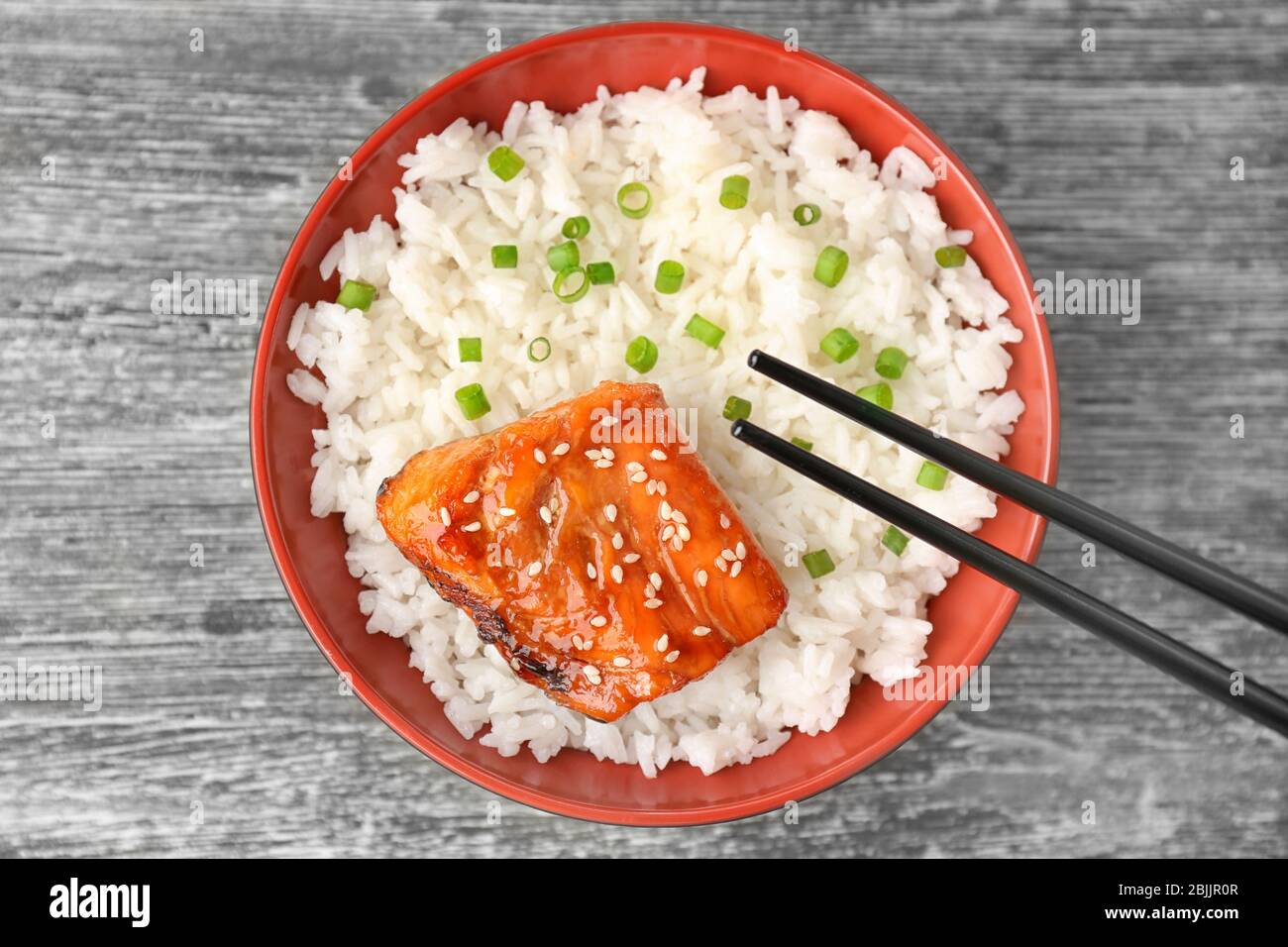Fish fillet served with rice in red bowl on grey background Stock Photo ...