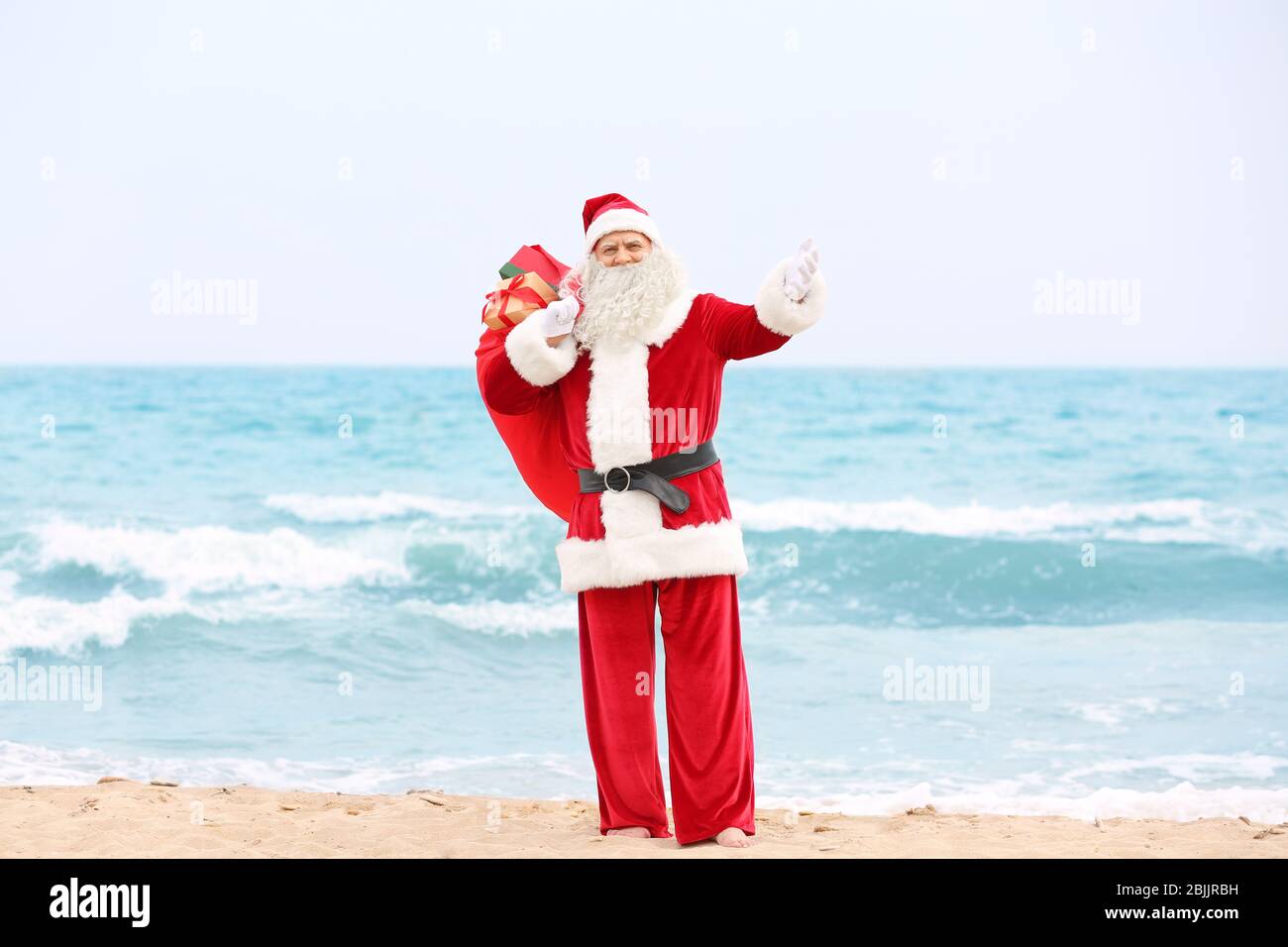 Authentic Santa Claus with big red bag full of gifts on beach Stock ...