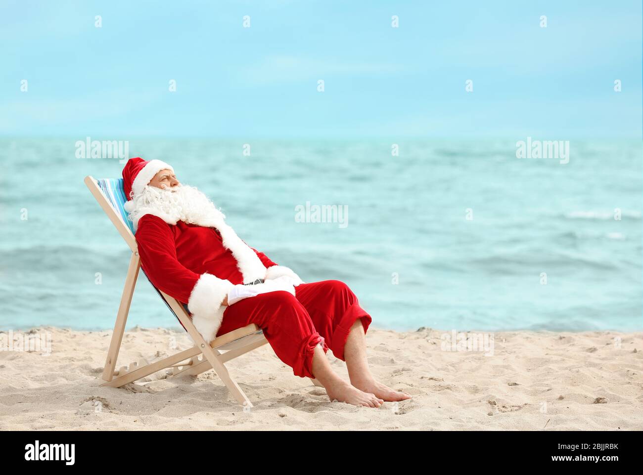 Authentic Santa Claus relaxing in deck chair on beach Stock Photo - Alamy
