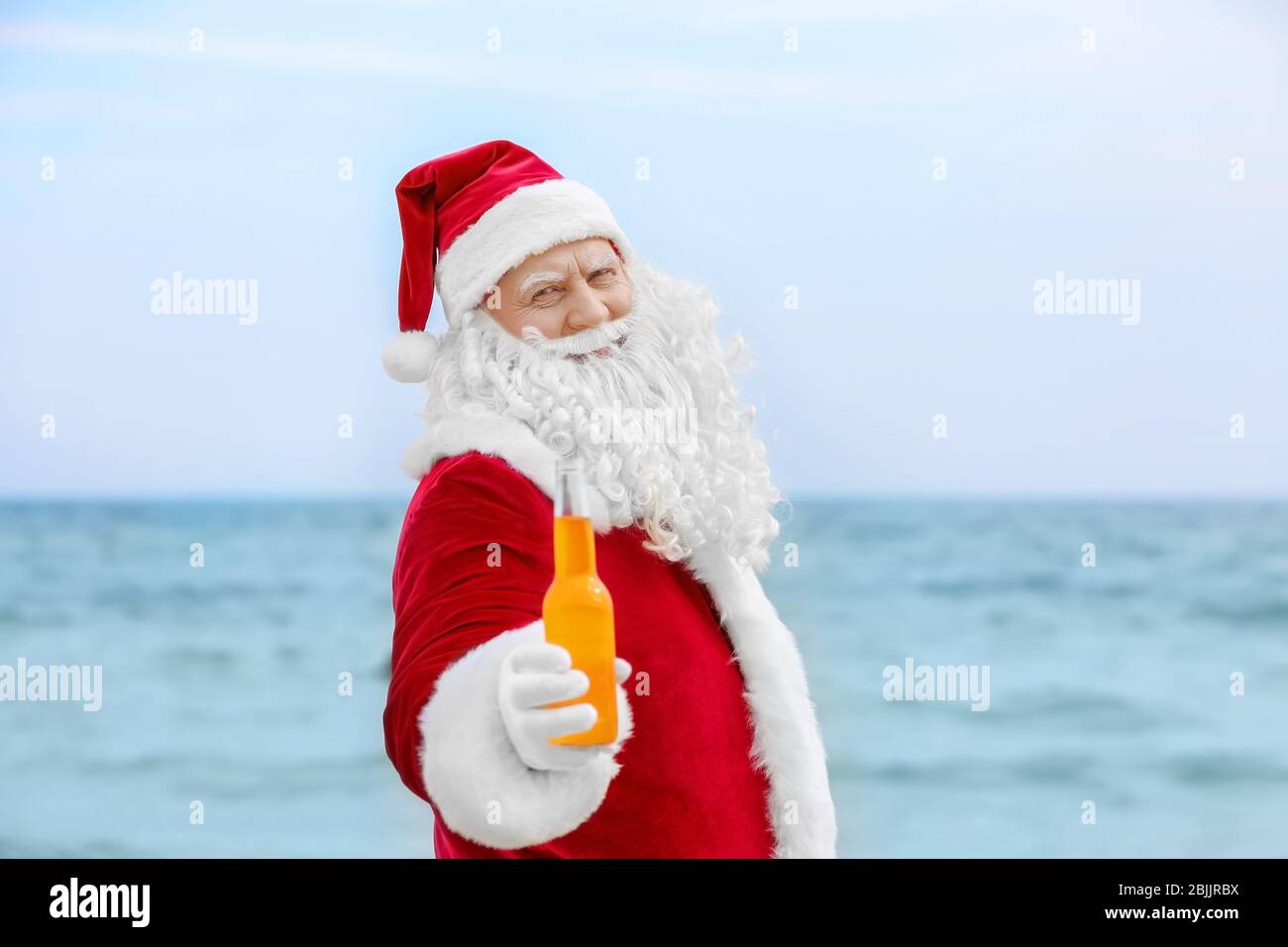 Authentic Santa Claus with bottle of drink on sea background Stock ...