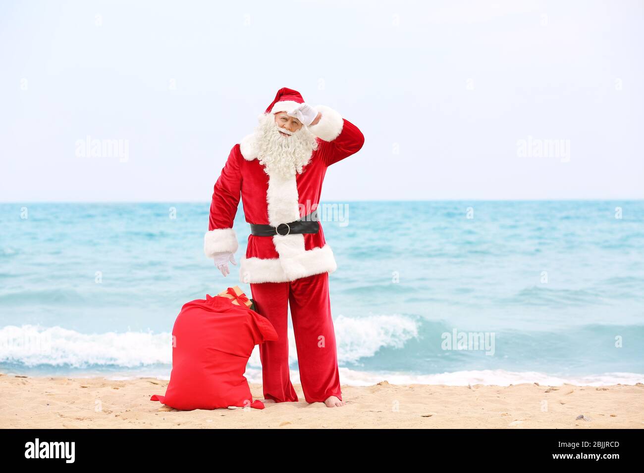 Authentic Santa Claus with big red bag full of gifts on beach Stock ...