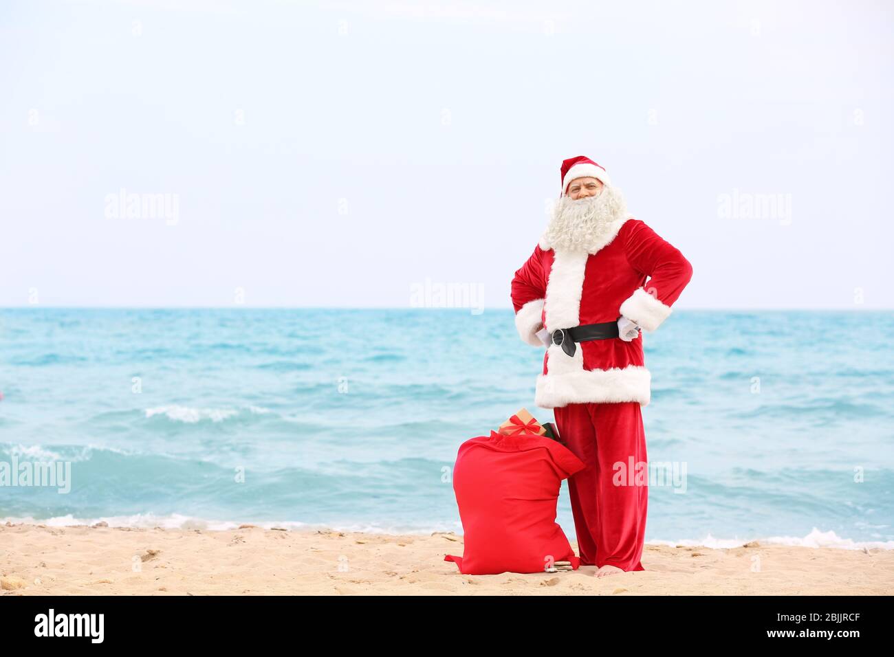 Authentic Santa Claus with big red bag full of gifts on beach Stock ...