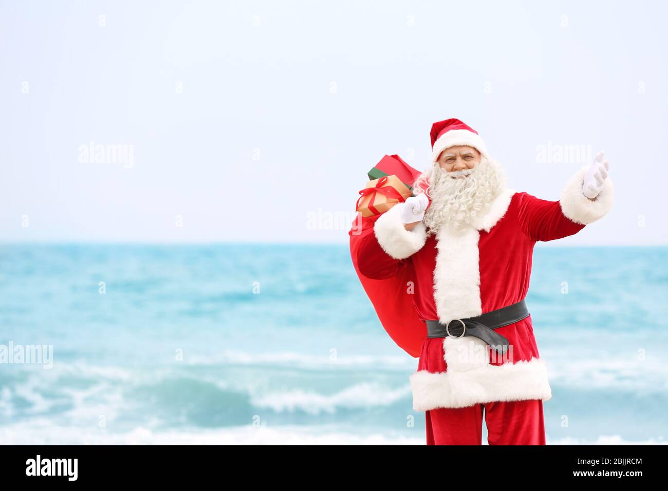 Authentic Santa Claus with big red bag full of gifts on sea background ...