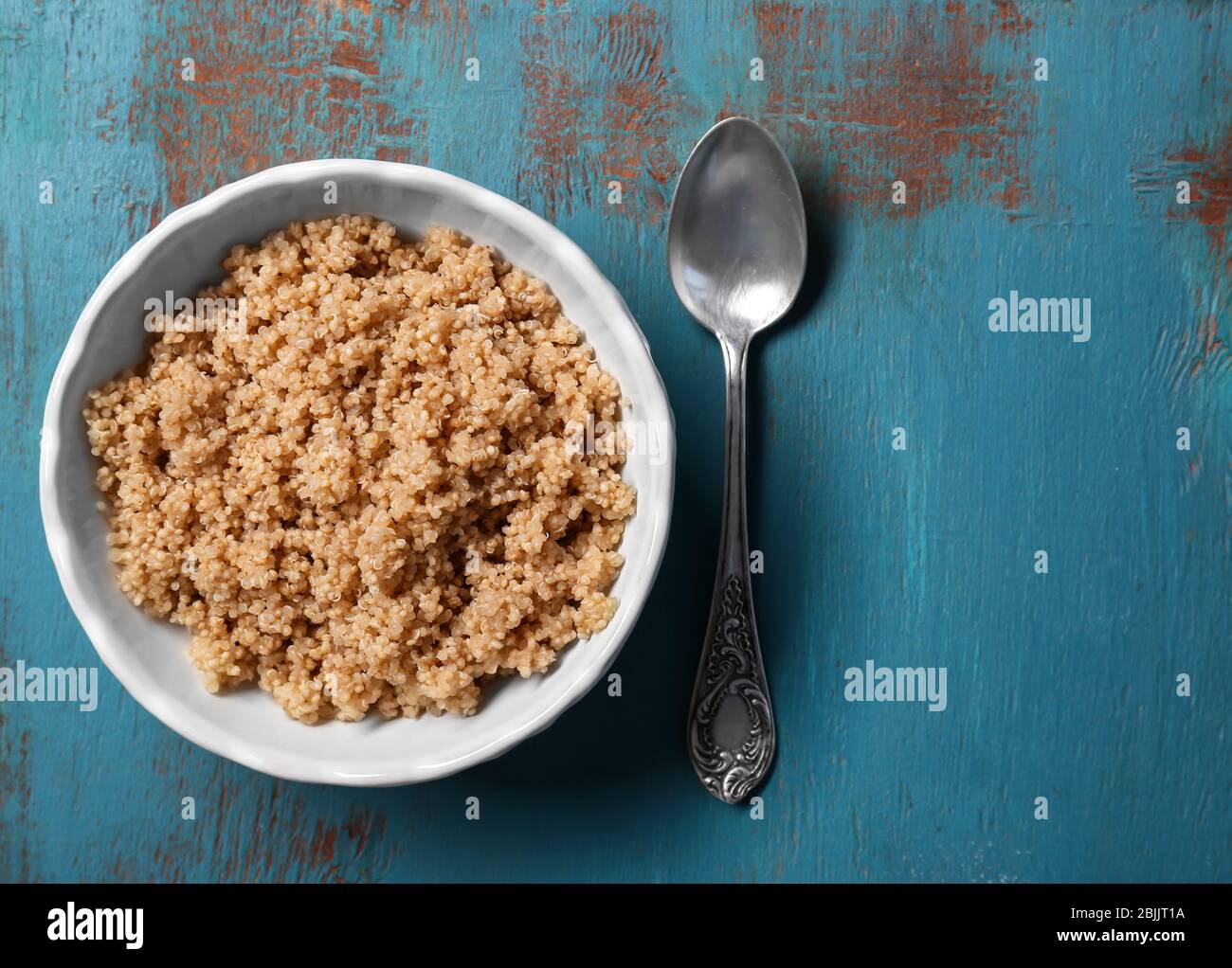 Cooked quinoa in bowl on blue wooden background Stock Photo - Alamy