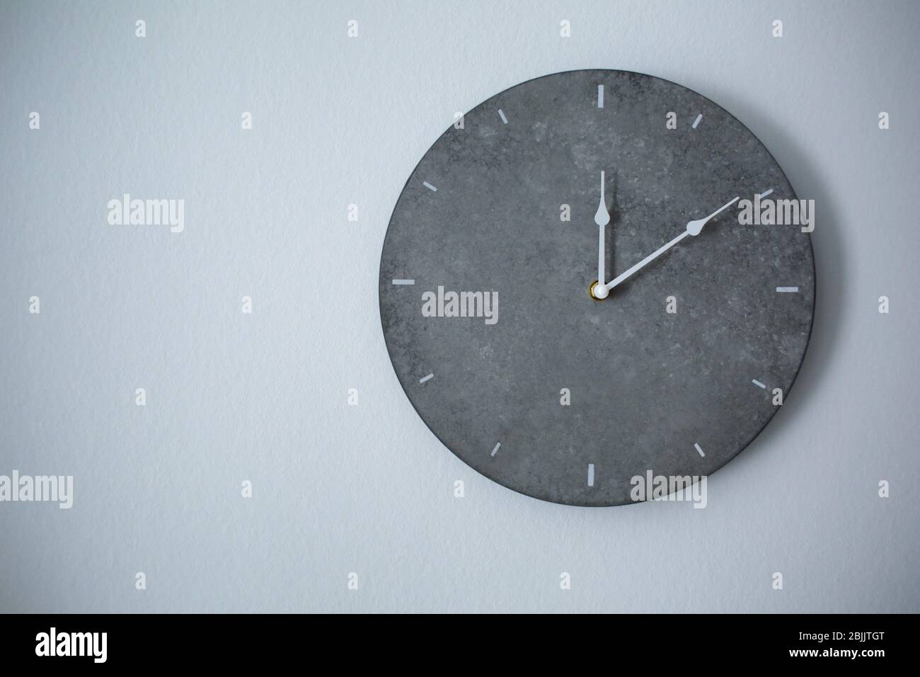 Big clock hanging on grey wall Stock Photo - Alamy