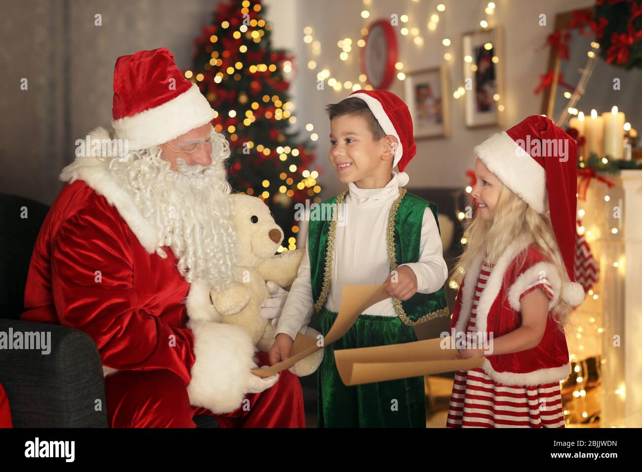 Cute elf kids showing letters to Santa in room with beautiful Christmas ...