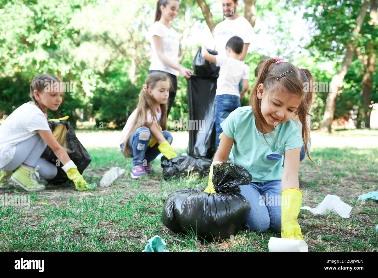 Young volunteers and children collecting garbage in park Stock Photo ...