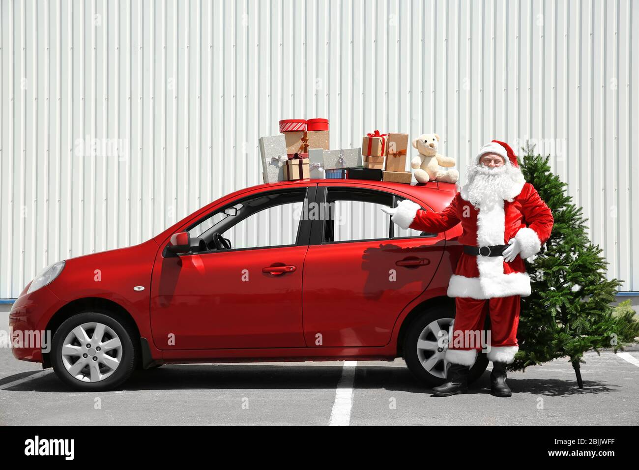 Authentic Santa near red car with gift boxes on it's top and Christmas ...