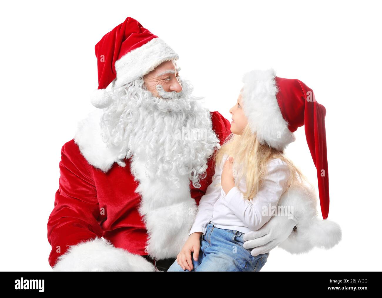 Cute little girl in Christmas hat sitting on Santa's lap against white ...