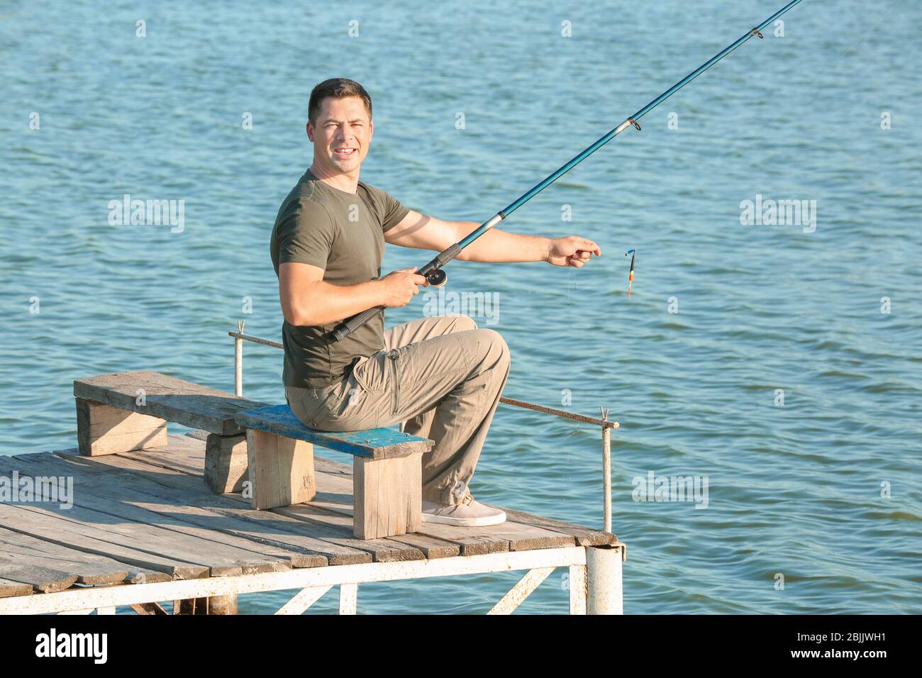 Man fishing from pier on river Stock Photo - Alamy