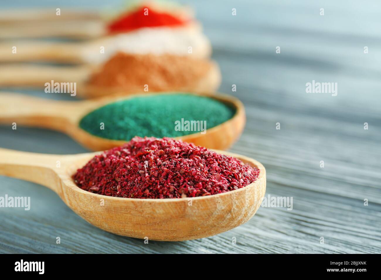Different colorful superfood powders in spoons on wooden table Stock ...