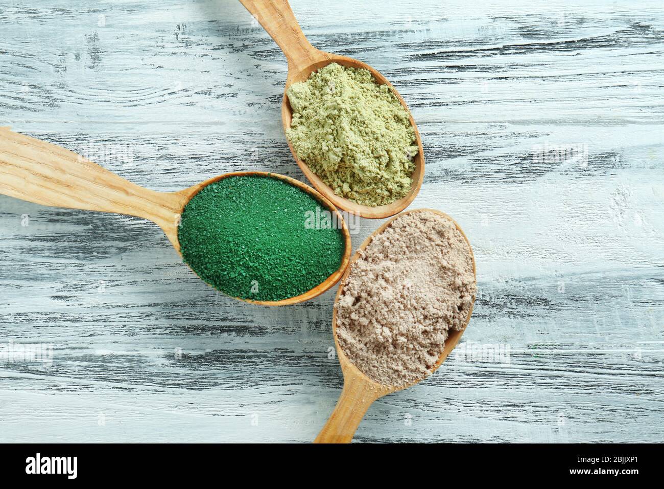 Different colorful superfood powders in spoons on wooden table Stock ...