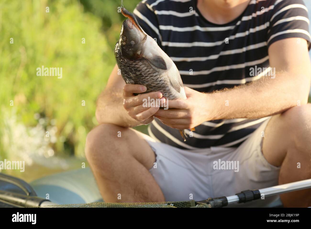 Young man holding fish, outdoors Stock Photo - Alamy