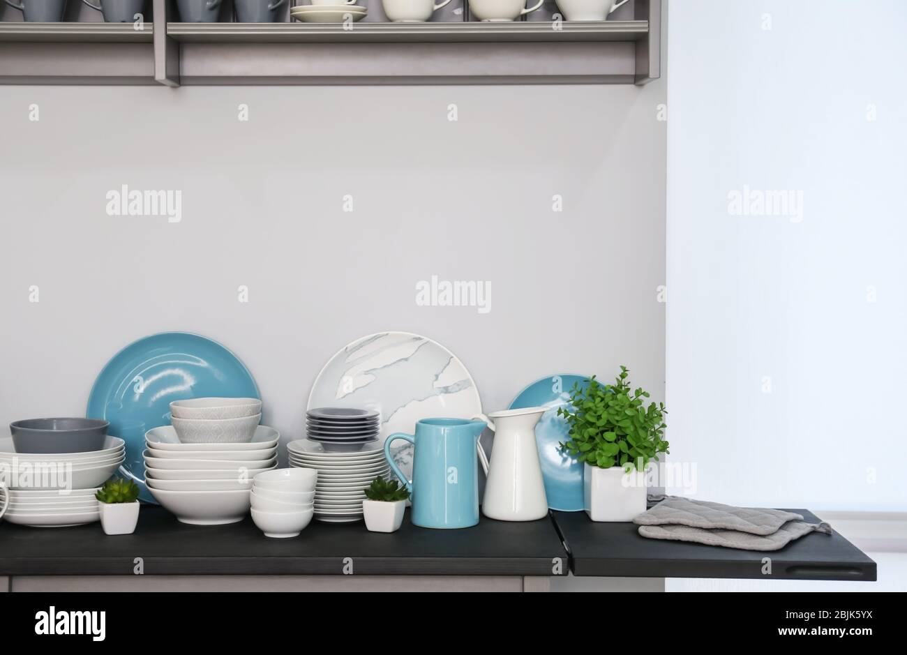 Cupboard with cups and different dishes on table in kitchen Stock Photo ...