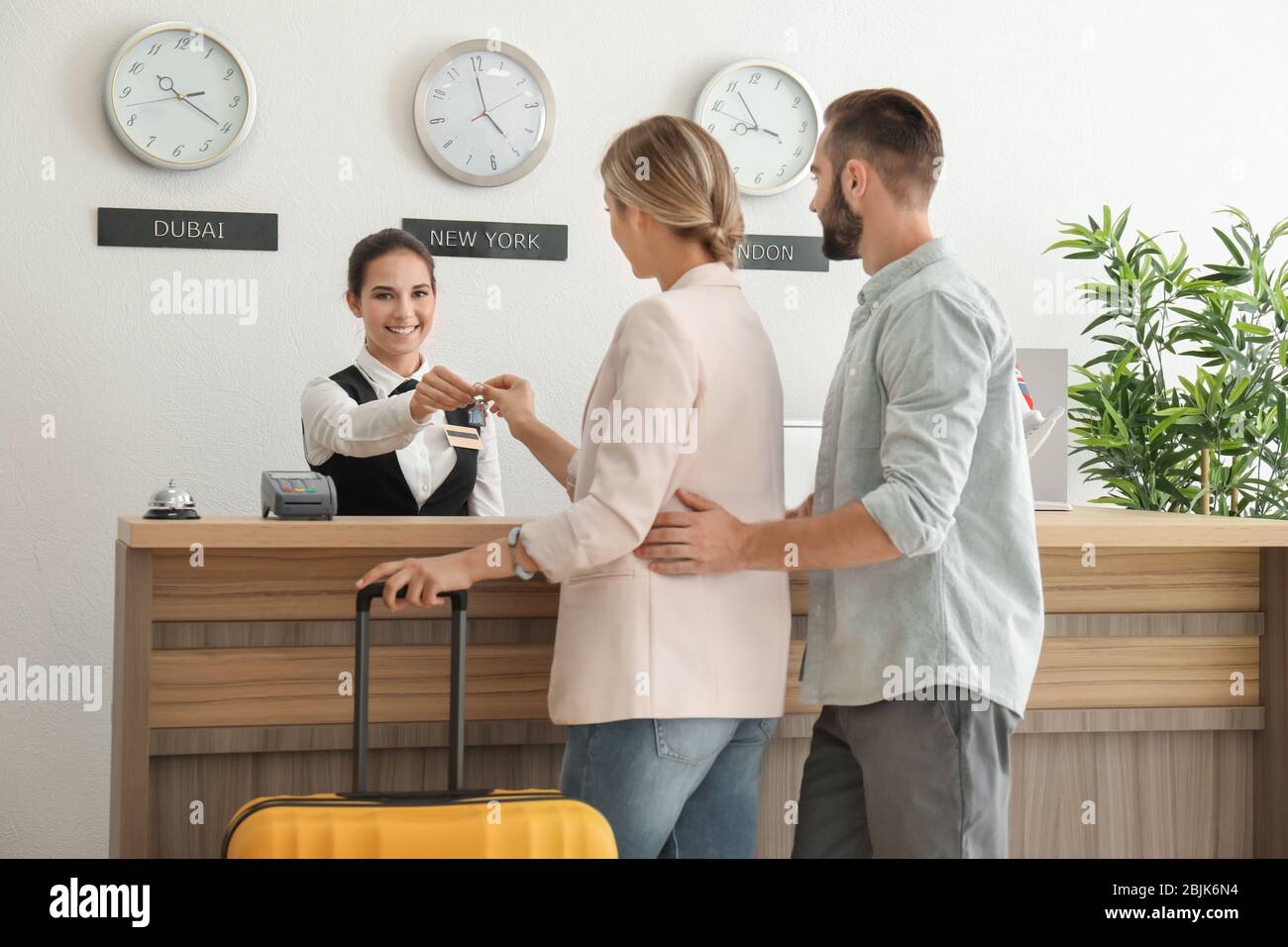 Young couple receiving key from hotel room at reception Stock Photo - Alamy