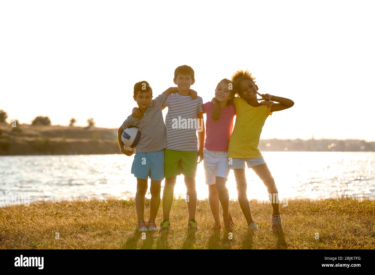 Cute children with ball on river bank Stock Photo - Alamy