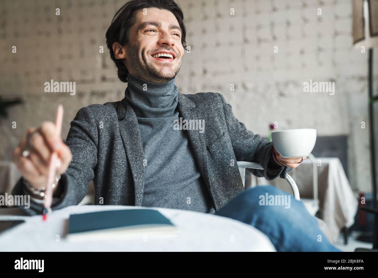 Image of handsome caucasian young man smiling and using cellphone while ...