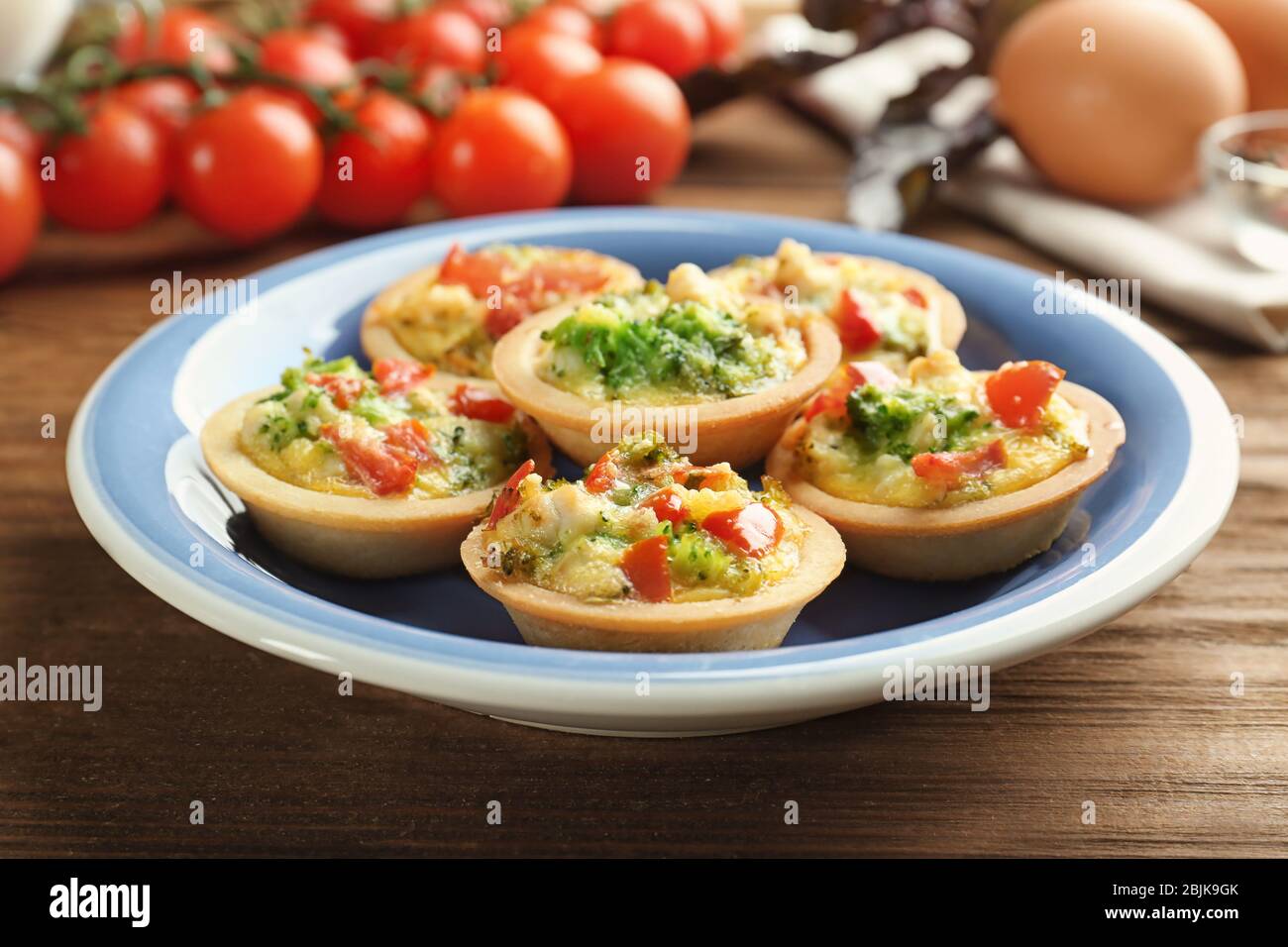 Plate with broccoli quiche tartlets on wooden table Stock Photo - Alamy