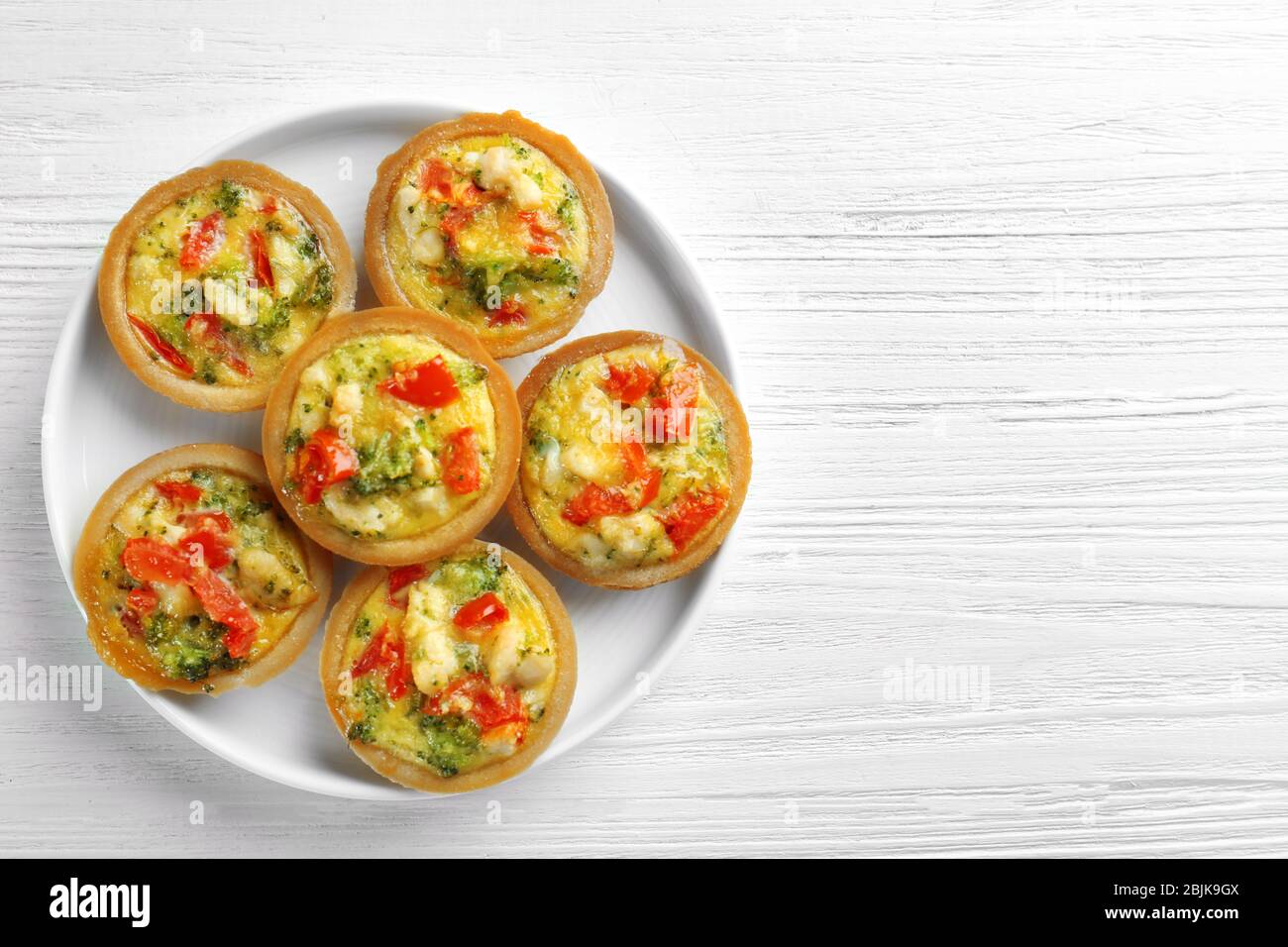 Plate with broccoli quiche tartlets on table Stock Photo - Alamy
