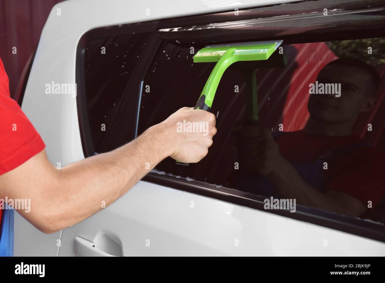 Man cleaning window of car with squeegee Stock Photo - Alamy
