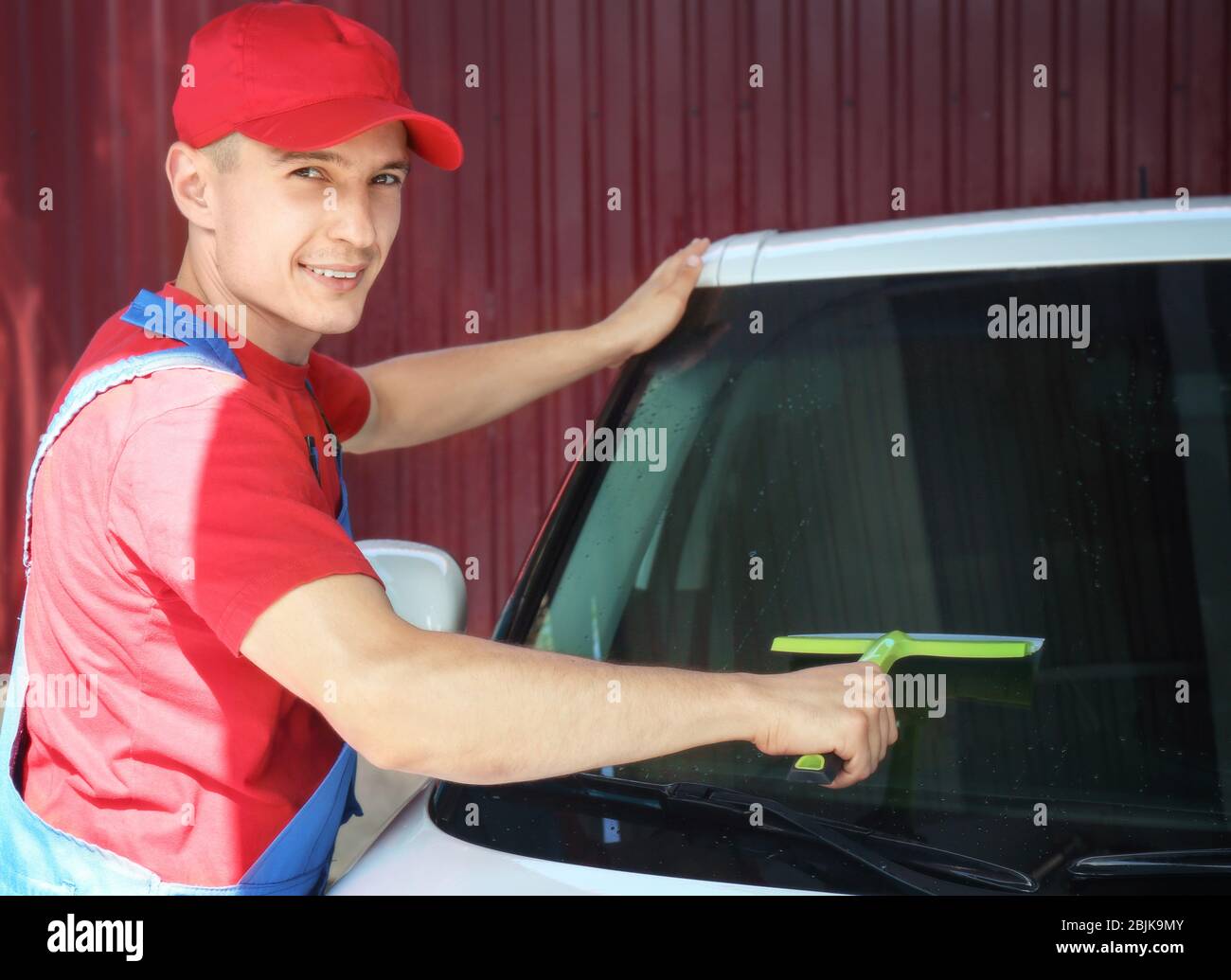 Man cleaning windshield with squeegee at car wash Stock Photo - Alamy