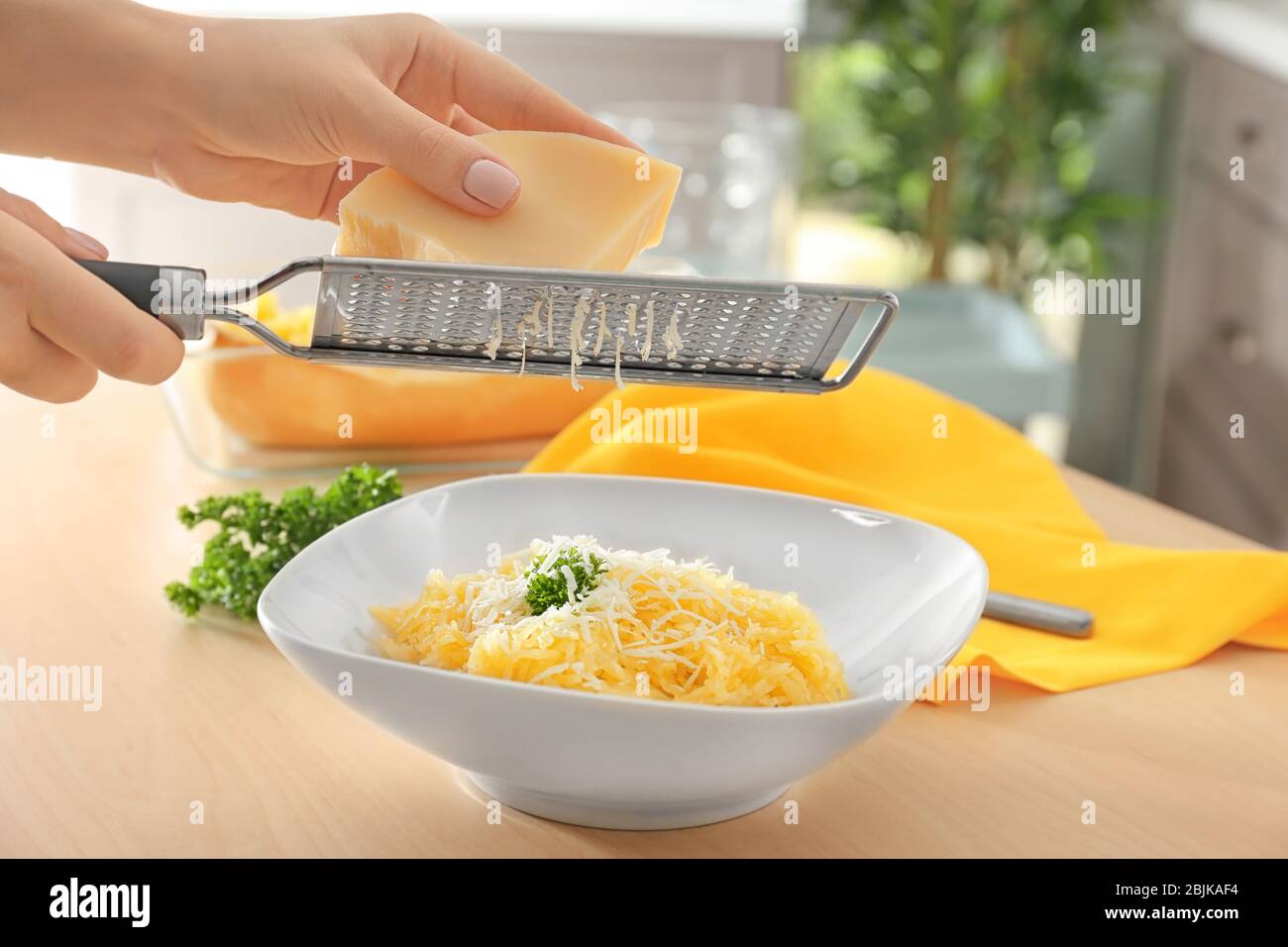Woman grating cheese on spaghetti squash in plate Stock Photo - Alamy