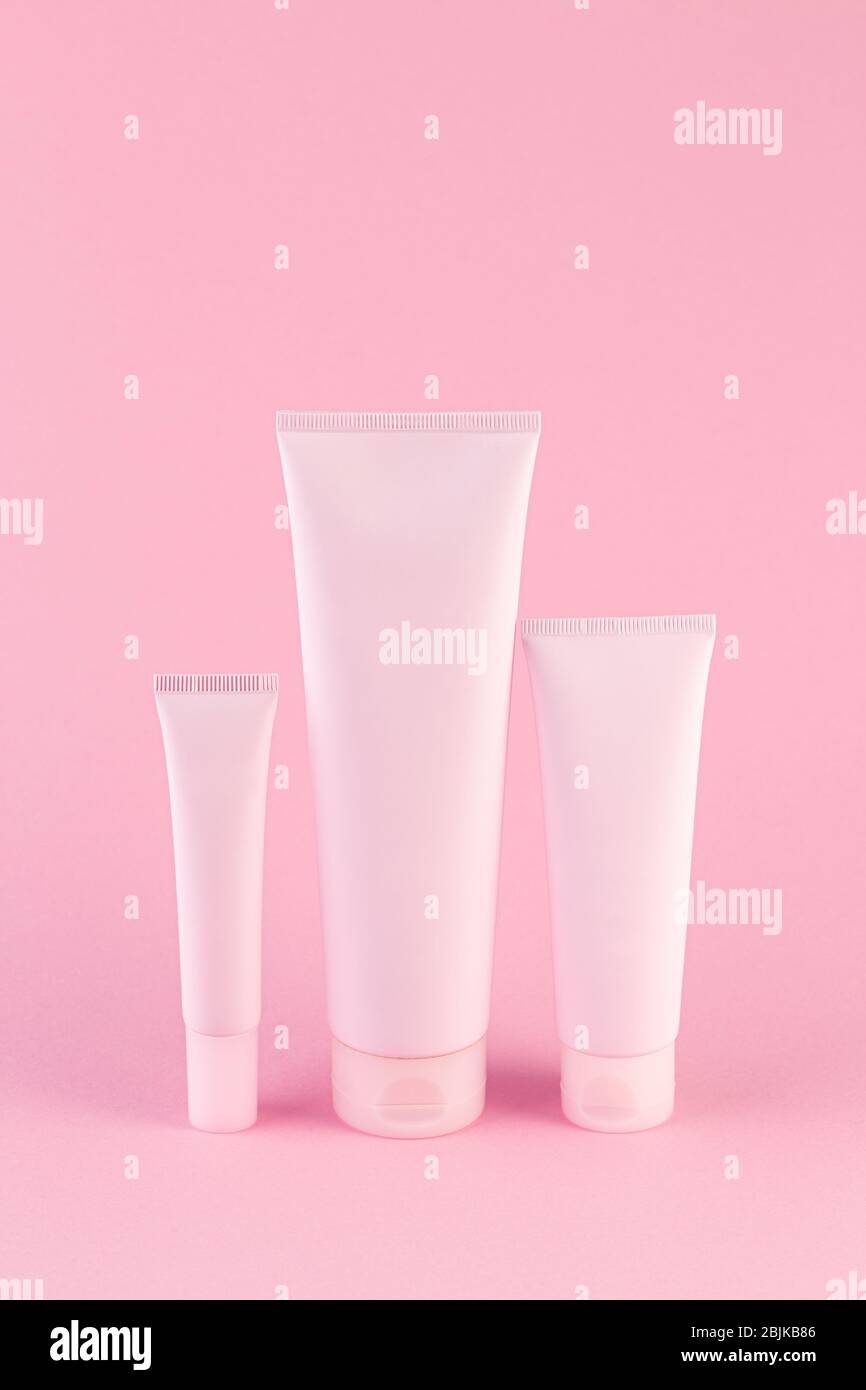 Collection of three cosmetic tubes on pastel pink background. Plastic ...