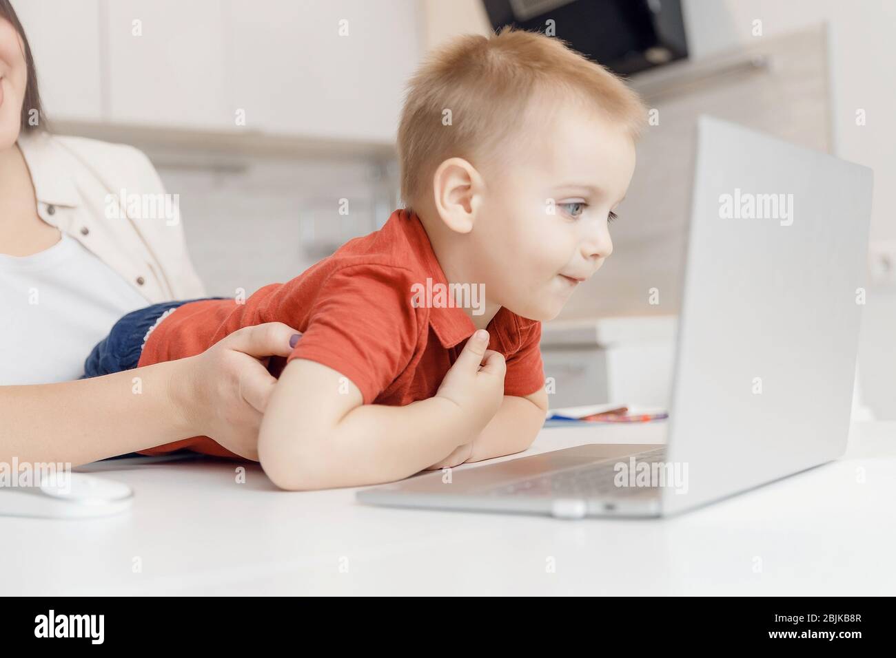 Boy child enthusiastically watching video blog or cartoons on laptop ...