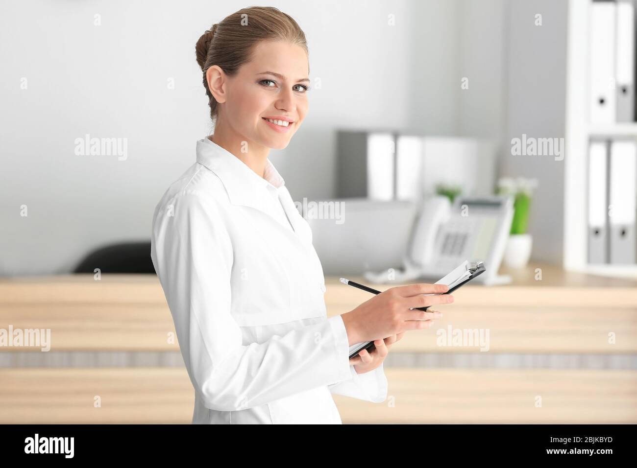Young female receptionist holding folder with documents in hospital ...