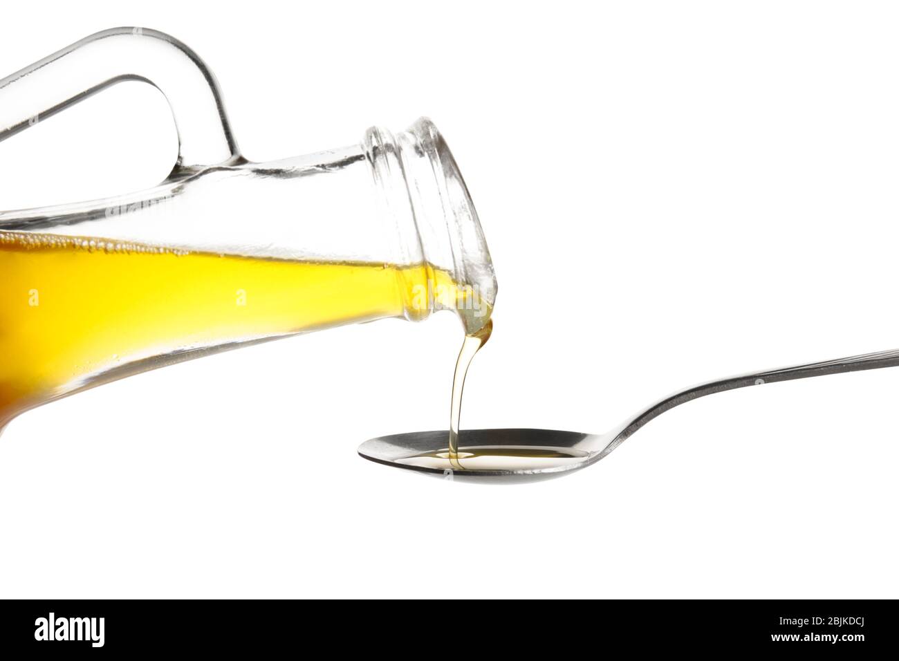 Pouring oil from glass pitcher into spoon, on white background Stock ...