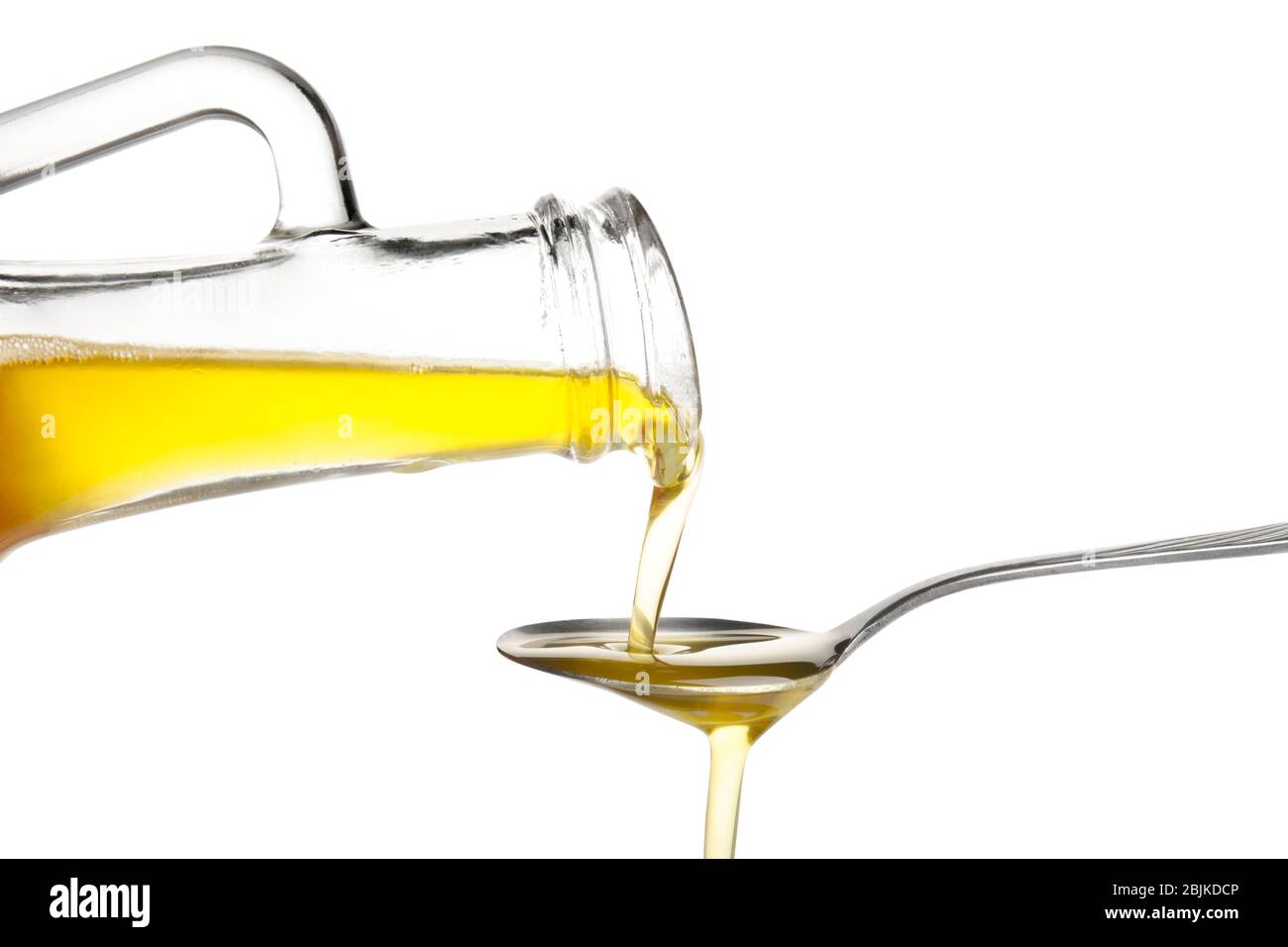 Pouring oil from glass pitcher into spoon, on white background Stock ...