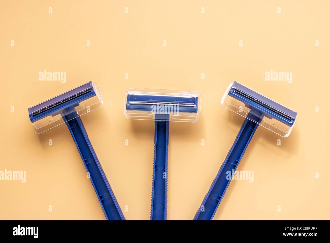 Set of three disposable razors in blue on a beige background. Banner ...