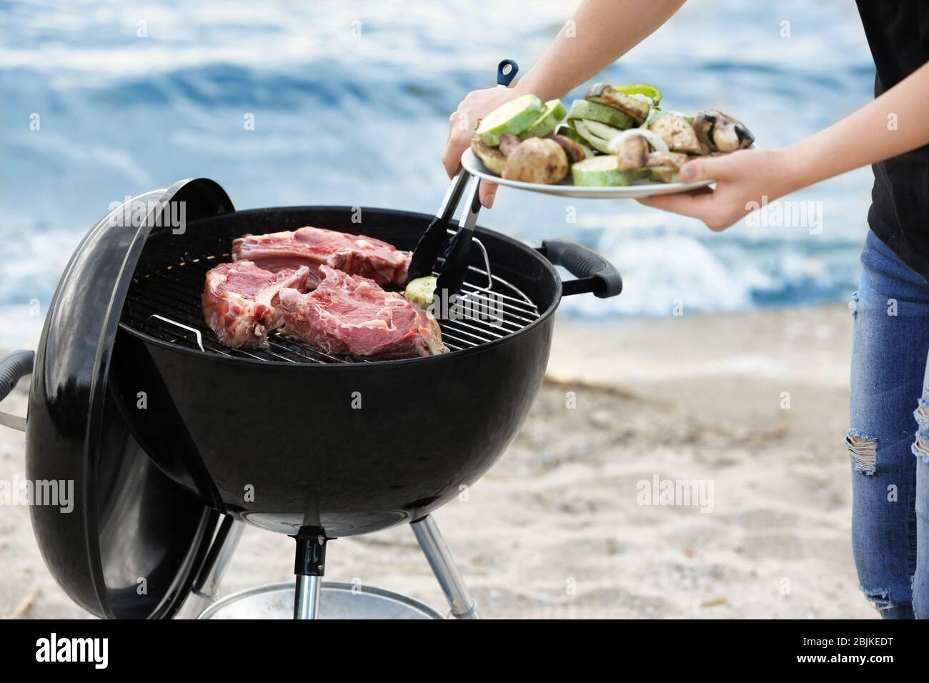Woman cooking tasty steaks and vegetables on barbecue grill, outdoors ...