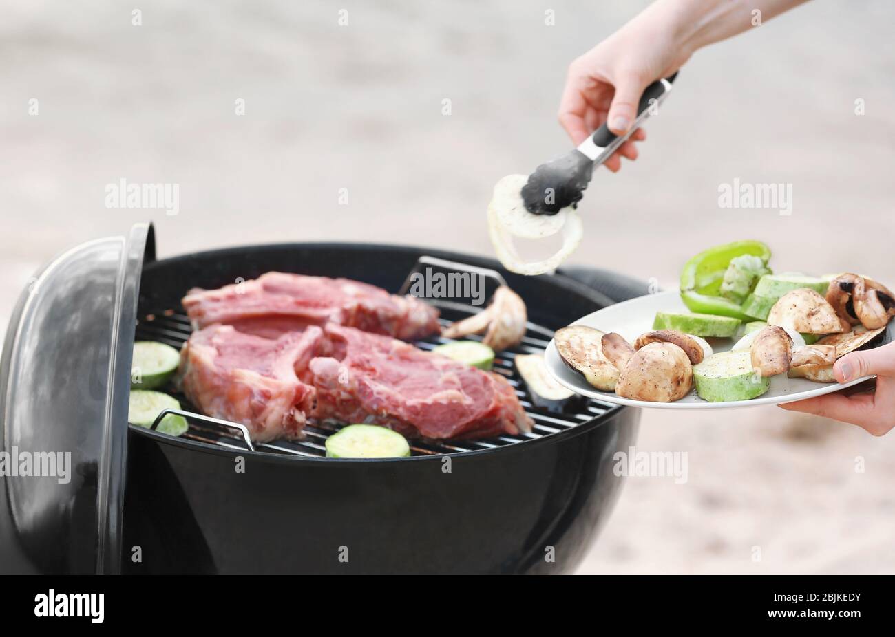 Woman cooking tasty steaks and vegetables on barbecue grill, closeup ...