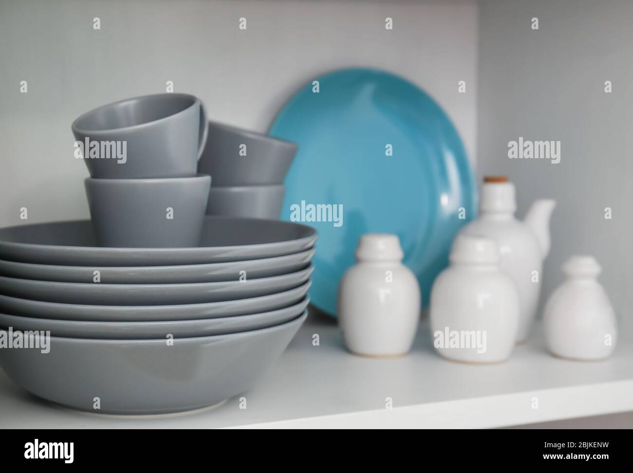 Ceramic dishware on white shelf indoors Stock Photo - Alamy