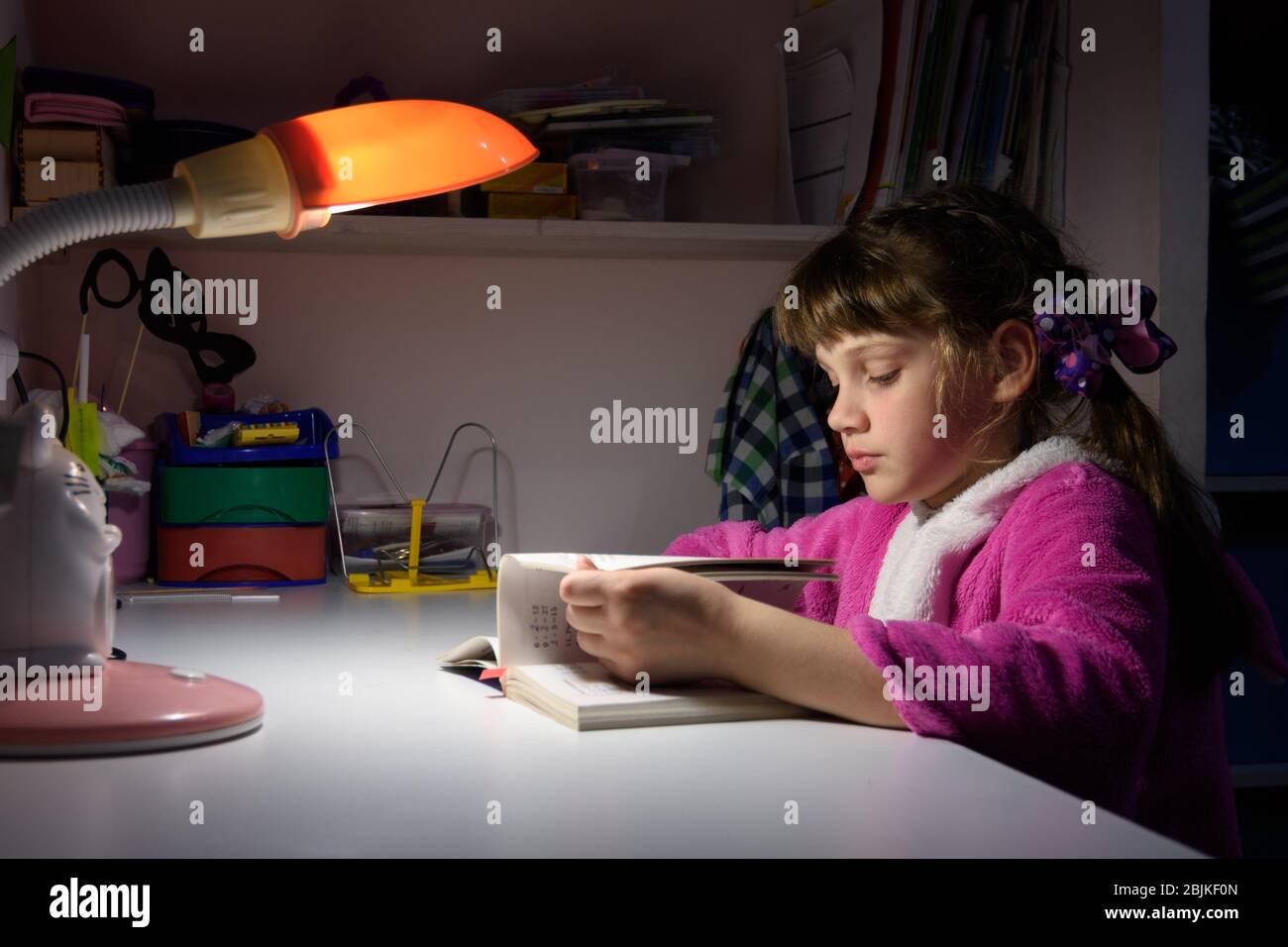 Girl at home doing homework under the light of a table lamp Stock Photo ...