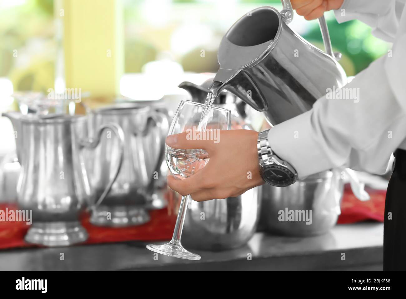 Waiter pouring water into glass in restaurant Stock Photo - Alamy