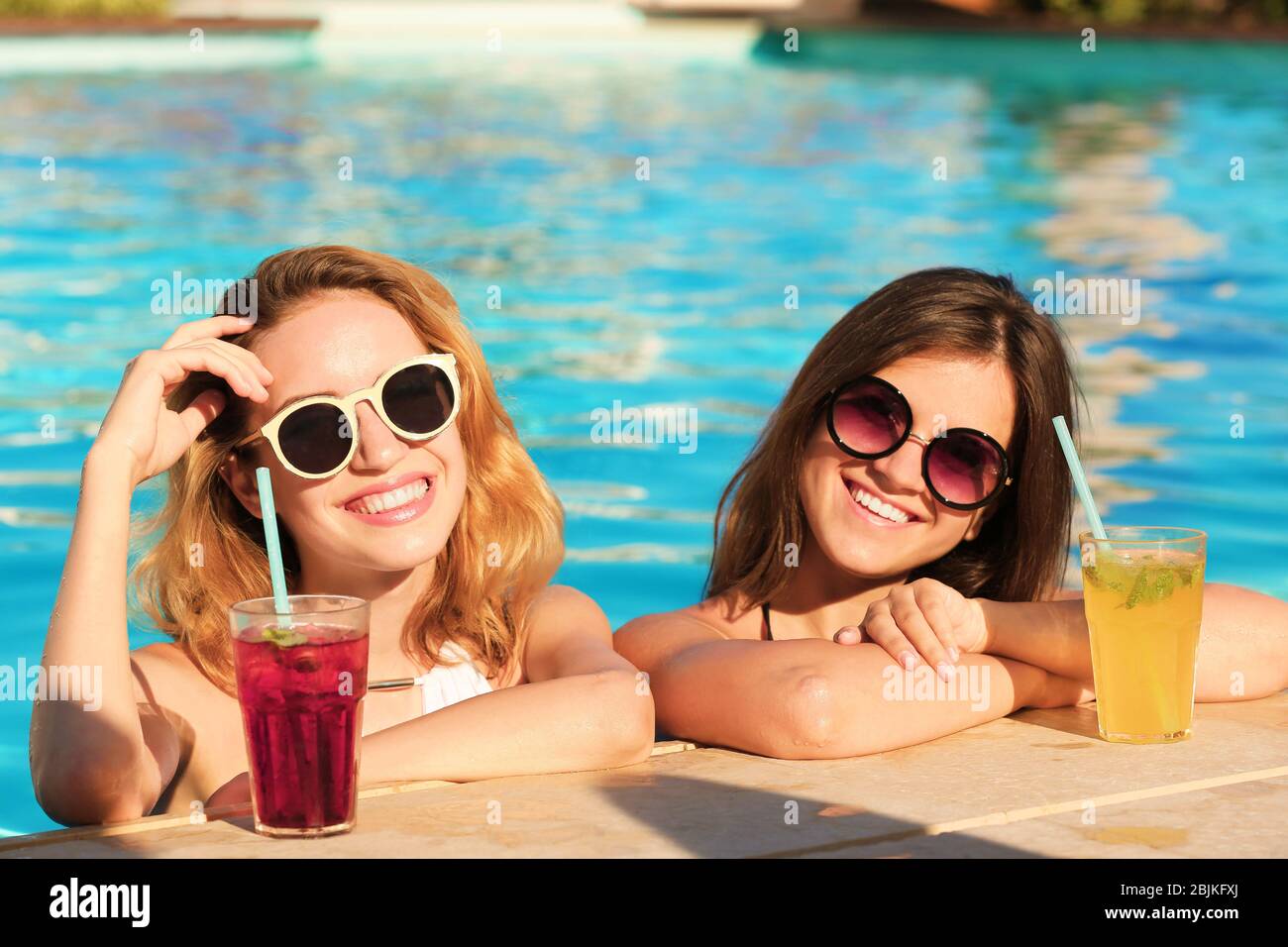 Beautiful women with cocktails relaxing in pool Stock Photo - Alamy