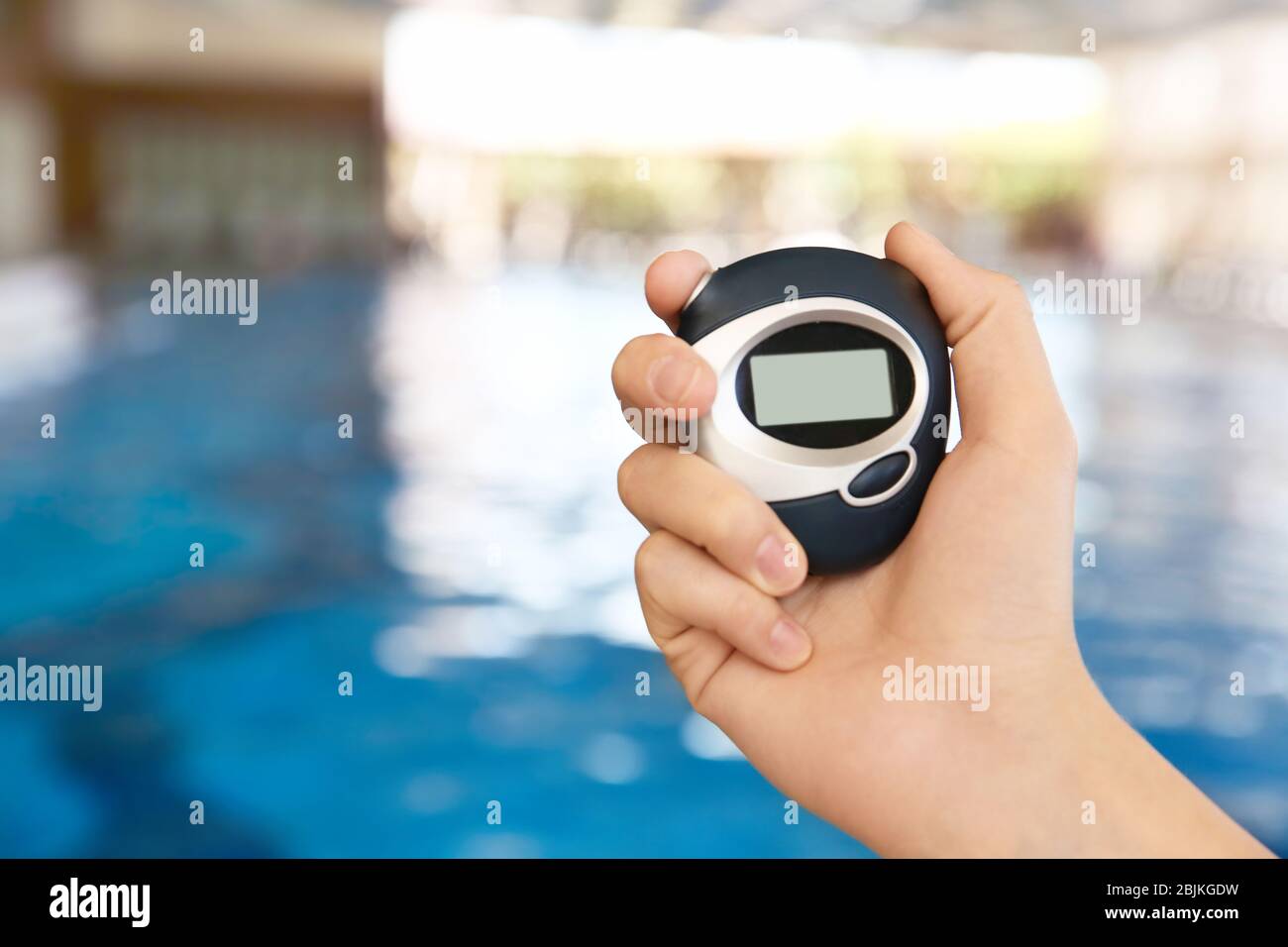 Hand of female coach holding stopwatch and blurred swimming pool on ...